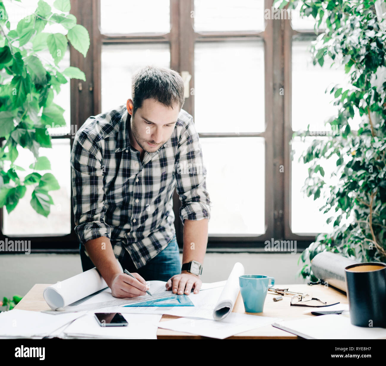 Young man architect working on architectural project in design studio ...