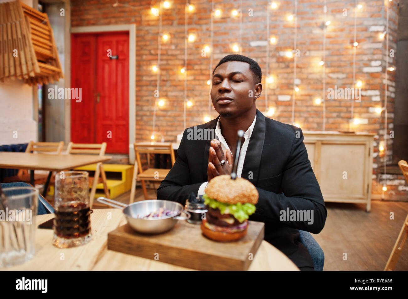 Pray before eat. Respectable young african american man in black suit ...