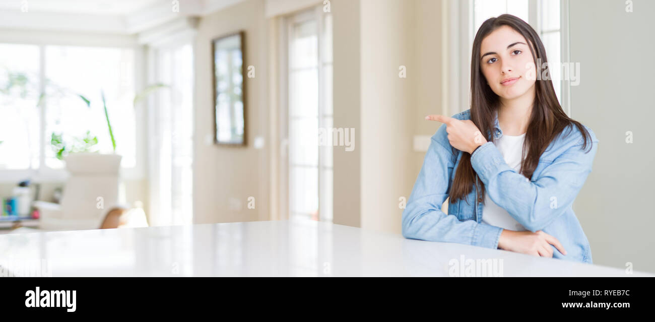 Wide angle picture of beautiful young woman sitting on white table at ...