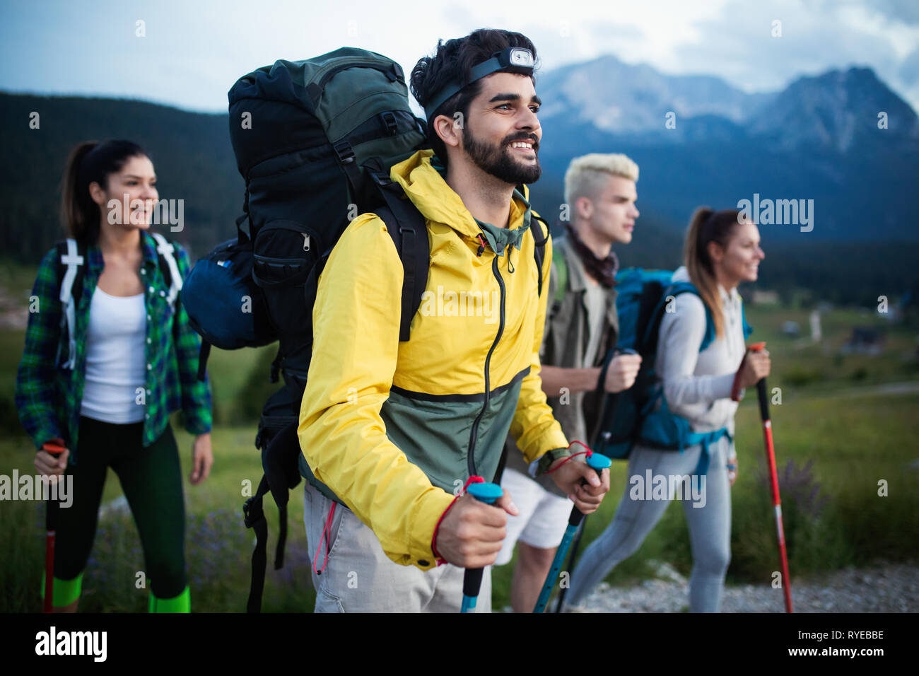 Group of hikers with backpacks and sticks walking on mountain. Friends ...