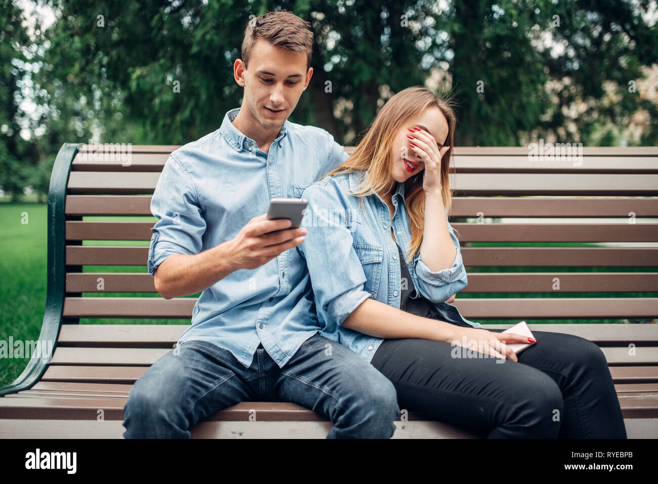 Phone addicted people, couple on the bench in park Stock Photo - Alamy