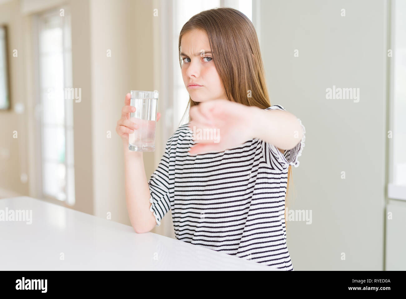 Beautiful young girl kid drinking a fresh glass of water with angry ...