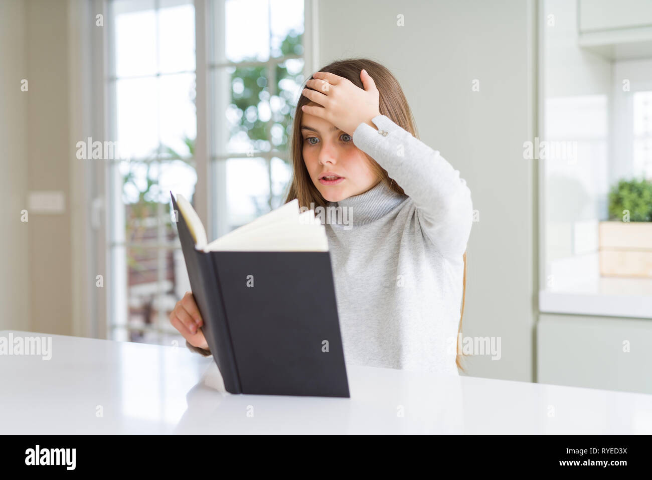 Beautiful young girl reading a book at home stressed with hand on head ...
