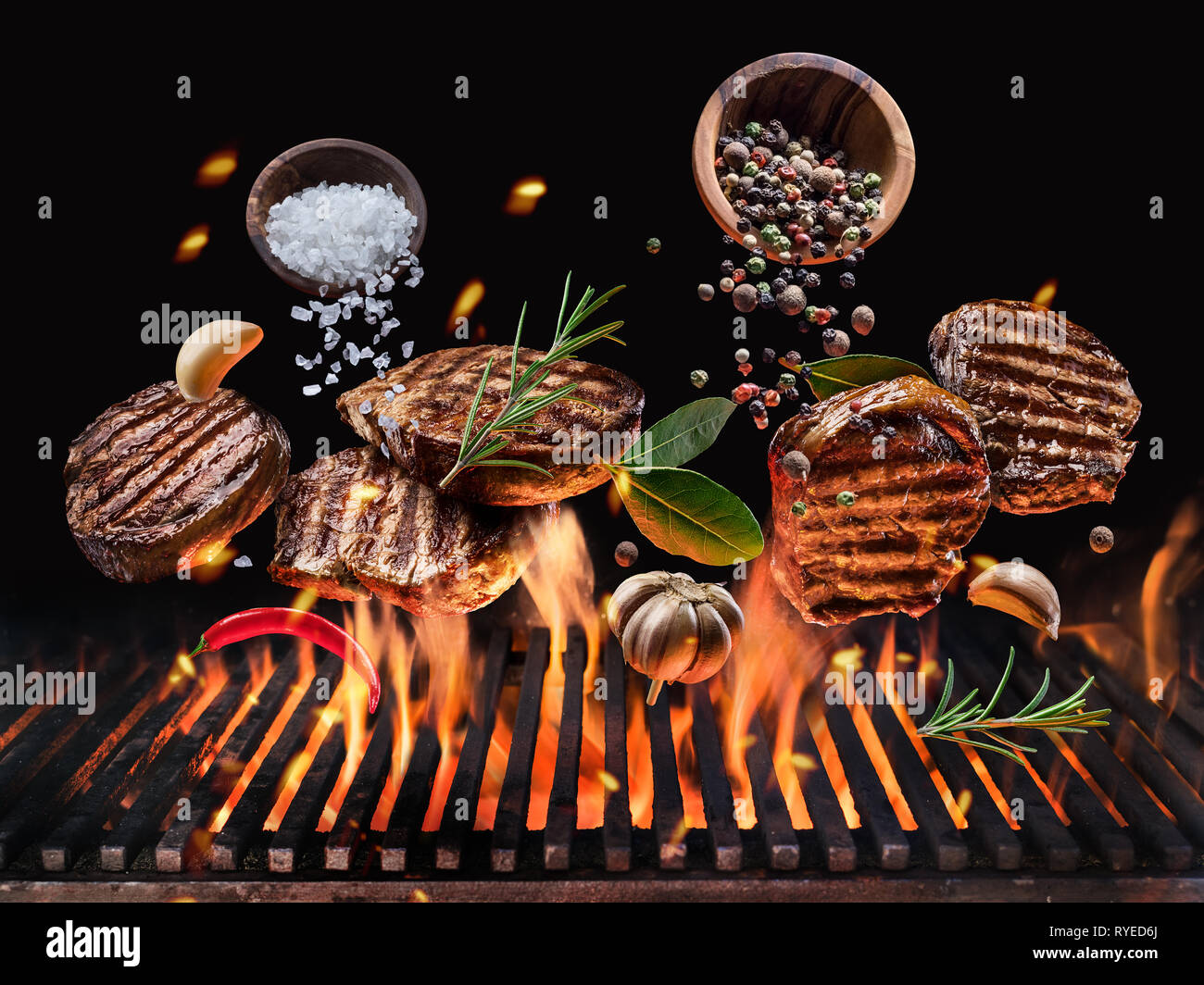 Grilled beef steaks with vegetables and spices fly over the blazing ...