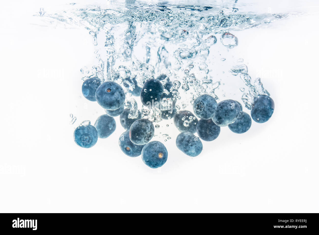 Bunch of delicious looking blueberries splashing into water surface and ...
