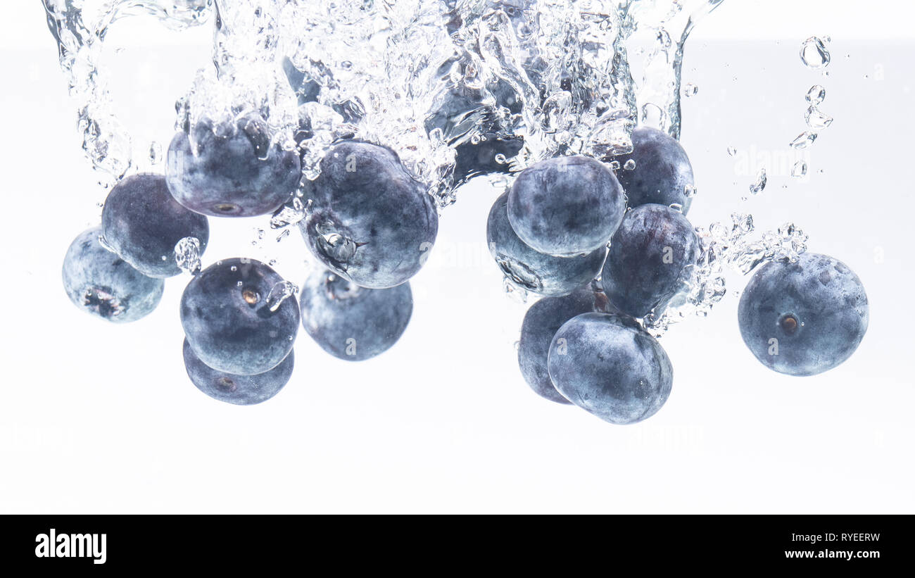 Bunch of delicious looking blueberries splashing into water surface and ...