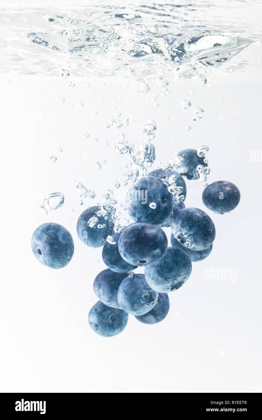 Bunch of delicious looking blueberries splashing into water surface and ...
