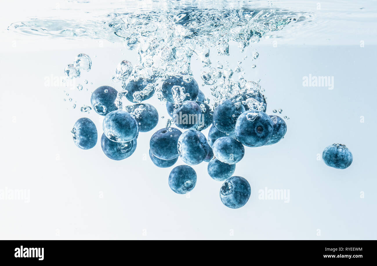 Bunch of delicious looking blueberries splashing into water surface and ...