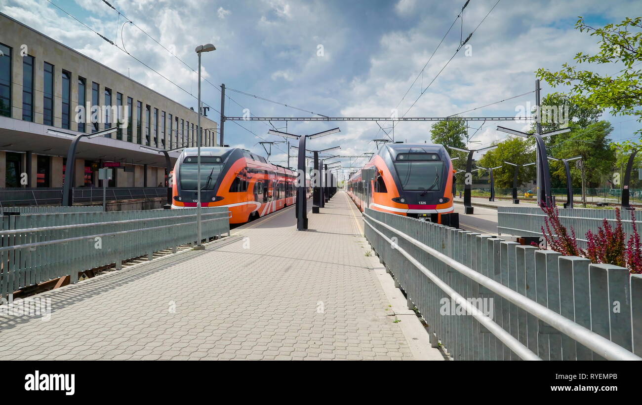 Two orange train on the railway stations in the city boarding some ...
