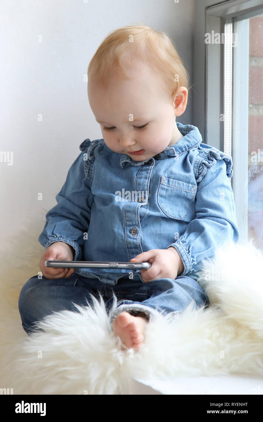 Toddler looks at its smartphone Stock Photo - Alamy