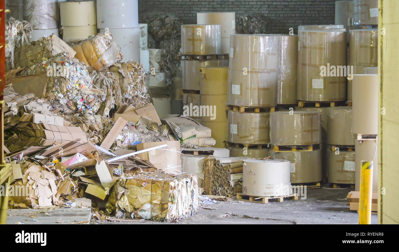 The paper rolls inside the paper mill factory with lots of the trash on ...