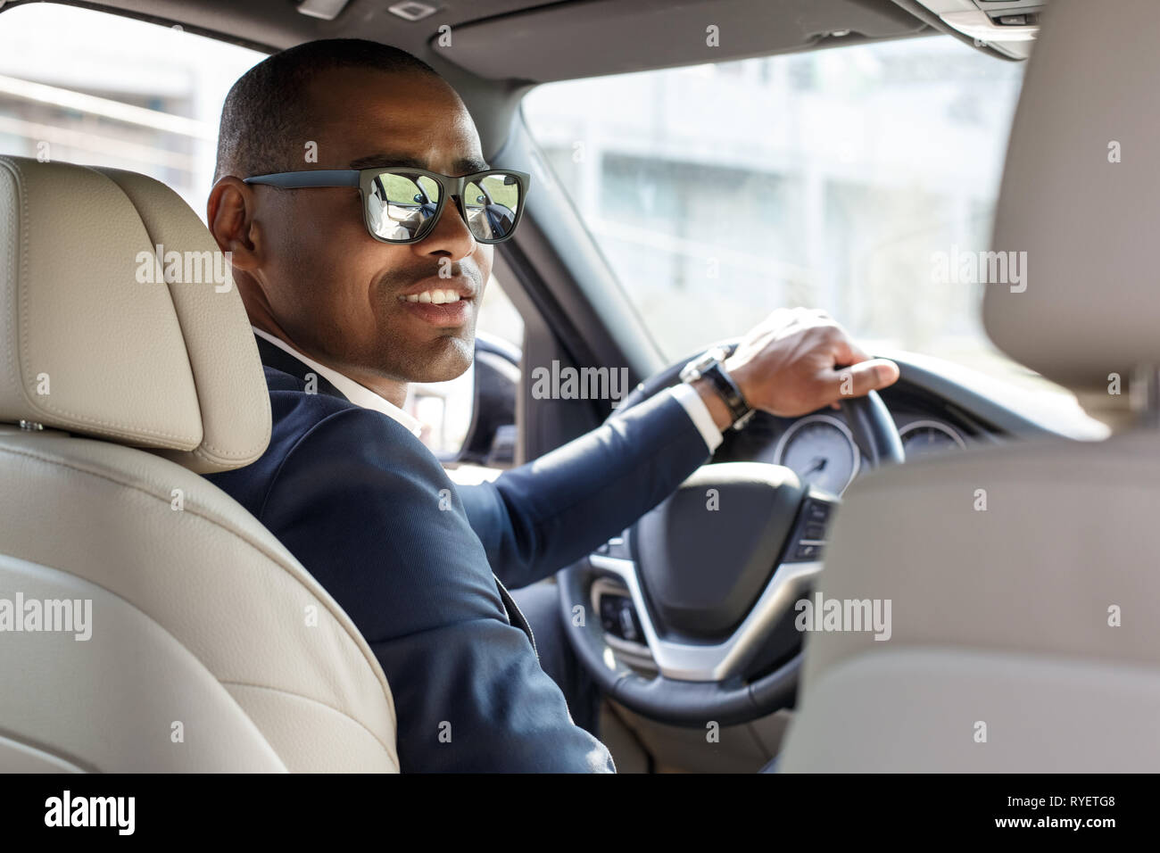 Young businessman driver in sunglasses sitting inside car driving ...