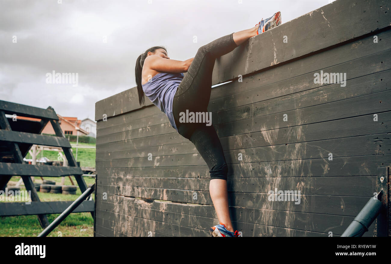 Participant in obstacle course climbing wall Stock Photo - Alamy