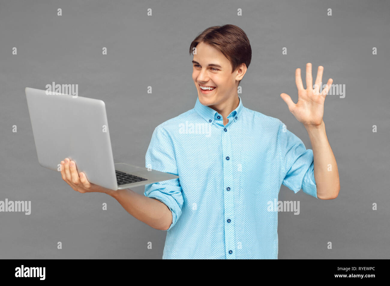 Freestyle. Teenager boy standing isolated on grey having video chat ...