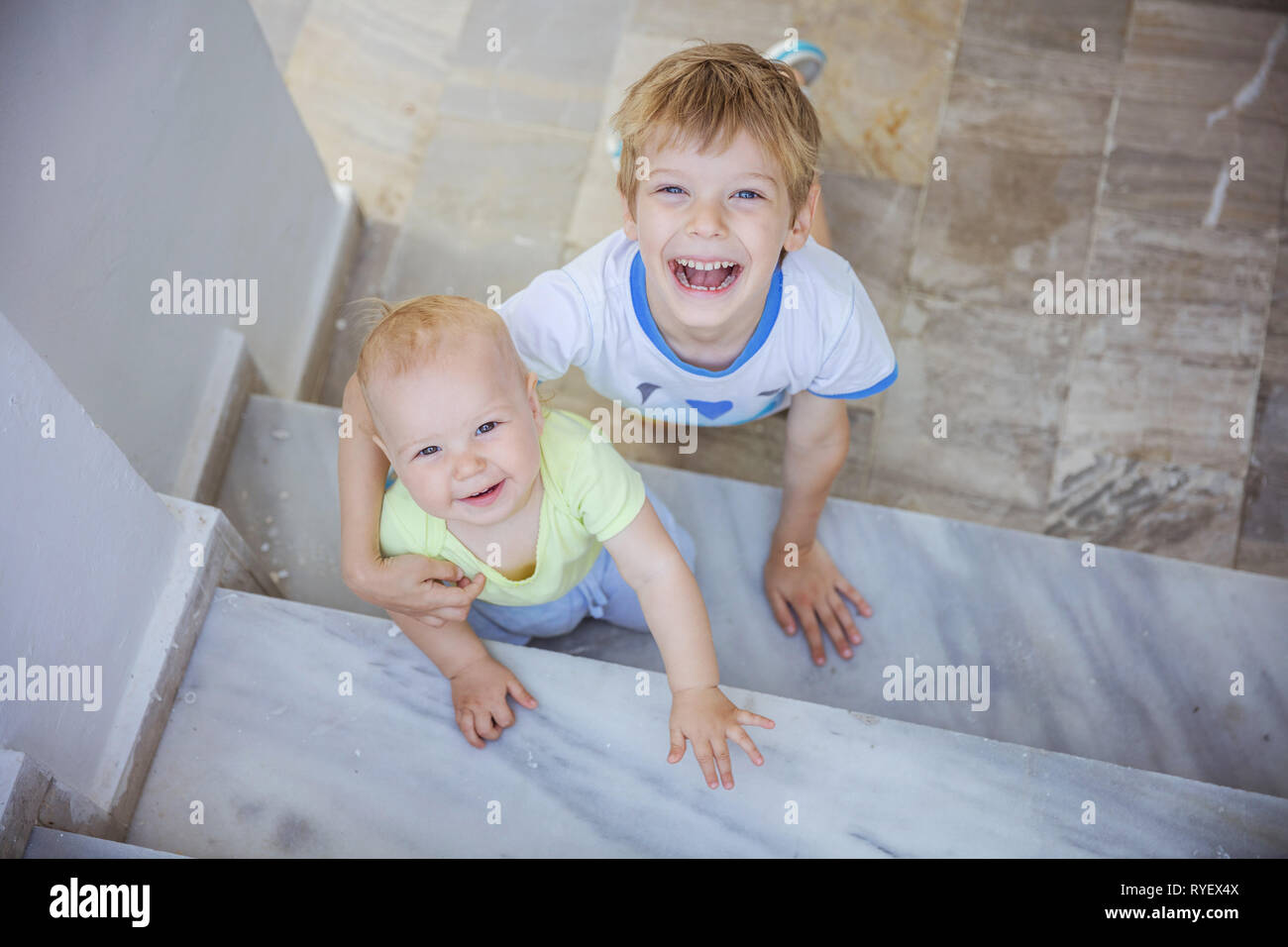 Preschool boy and baby girl looking up at camera and smiling outdoors ...