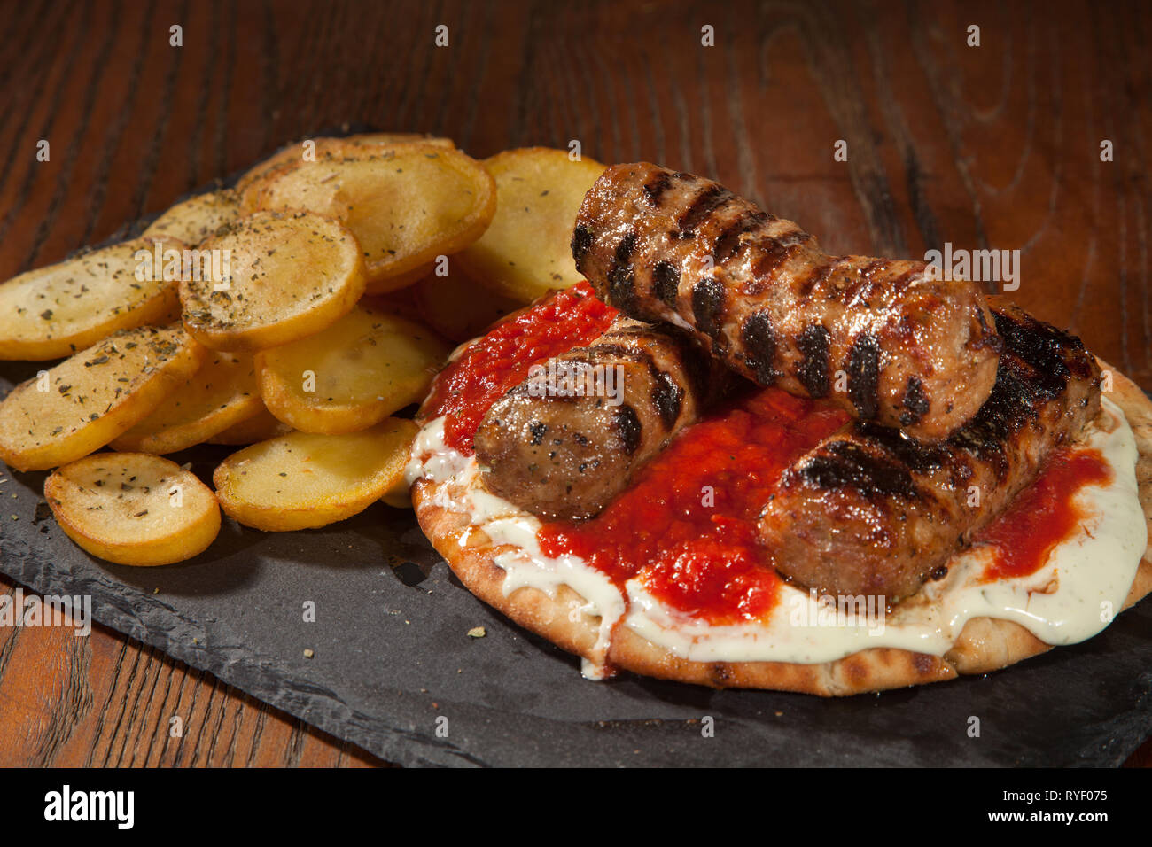 soutzoukaki beef meat burger served with fried potatoes and red sauce ...