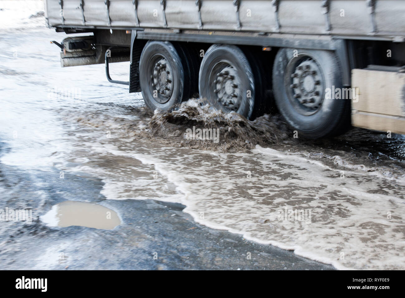 dirty wave of spray from under the wheels of a truck. Water on the road ...