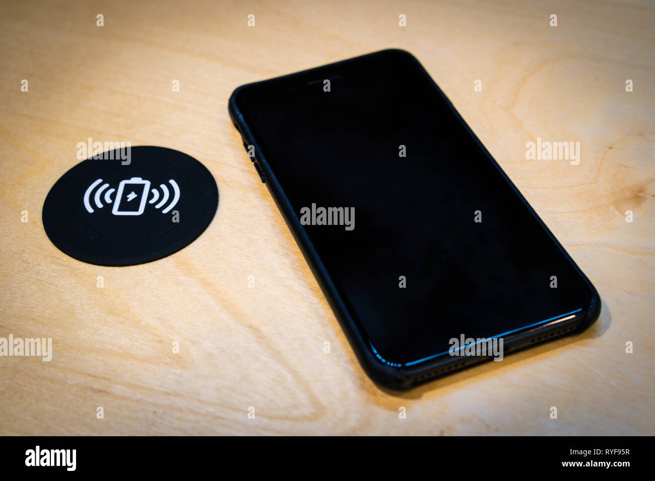 Smartphone charging on a table with a wireless charging pad. Wireless ...