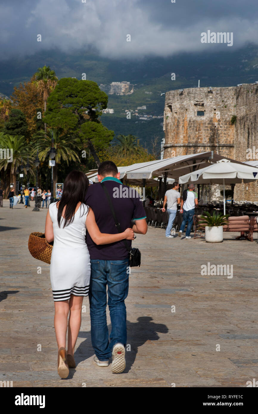 Couple walking on the promenade just outside the old town walls, Budva ...