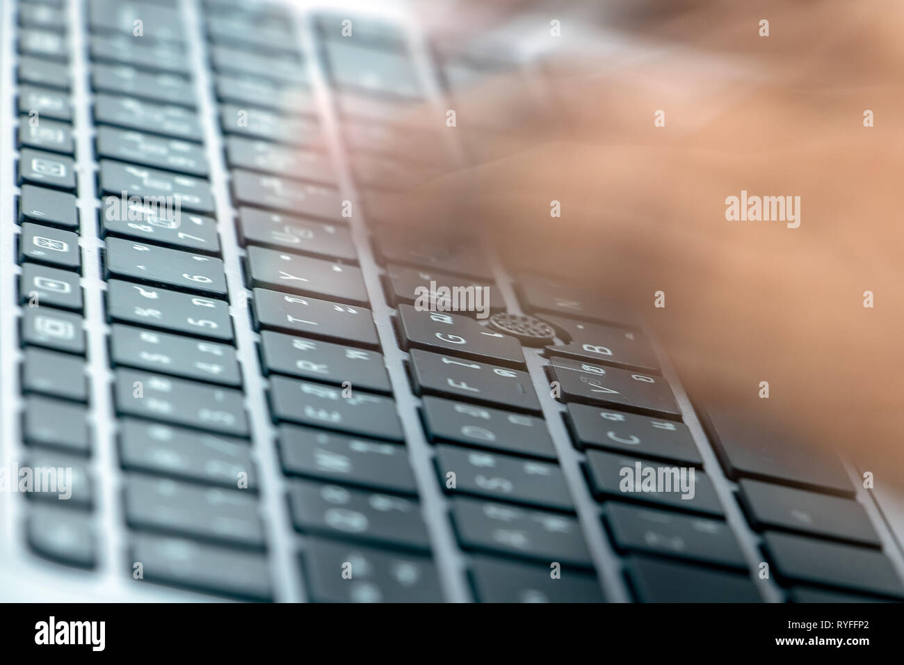 Close-up view of blurred female hand write on keyboard of notebook ...