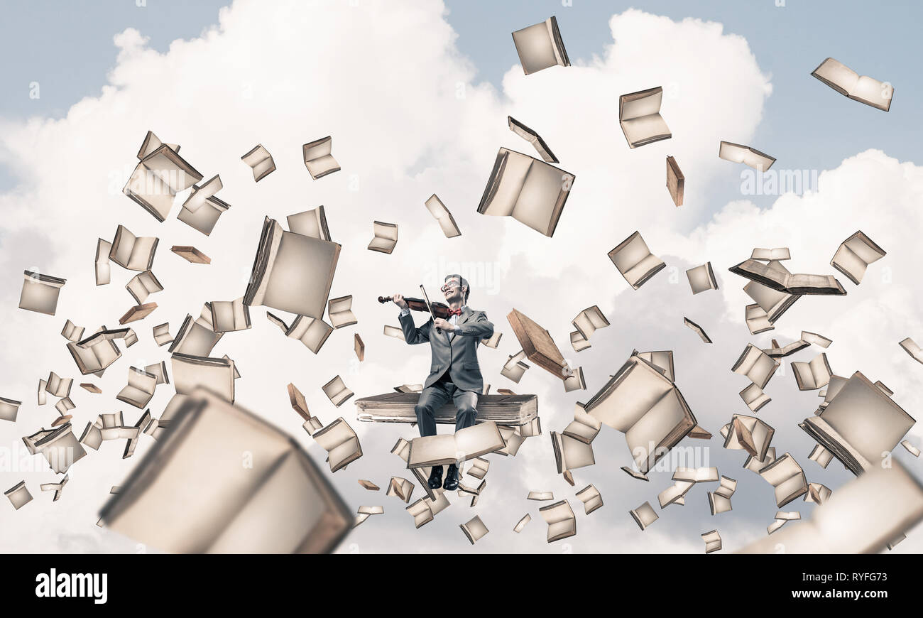 Handsome violinist sitting on book and play his melody Stock Photo - Alamy