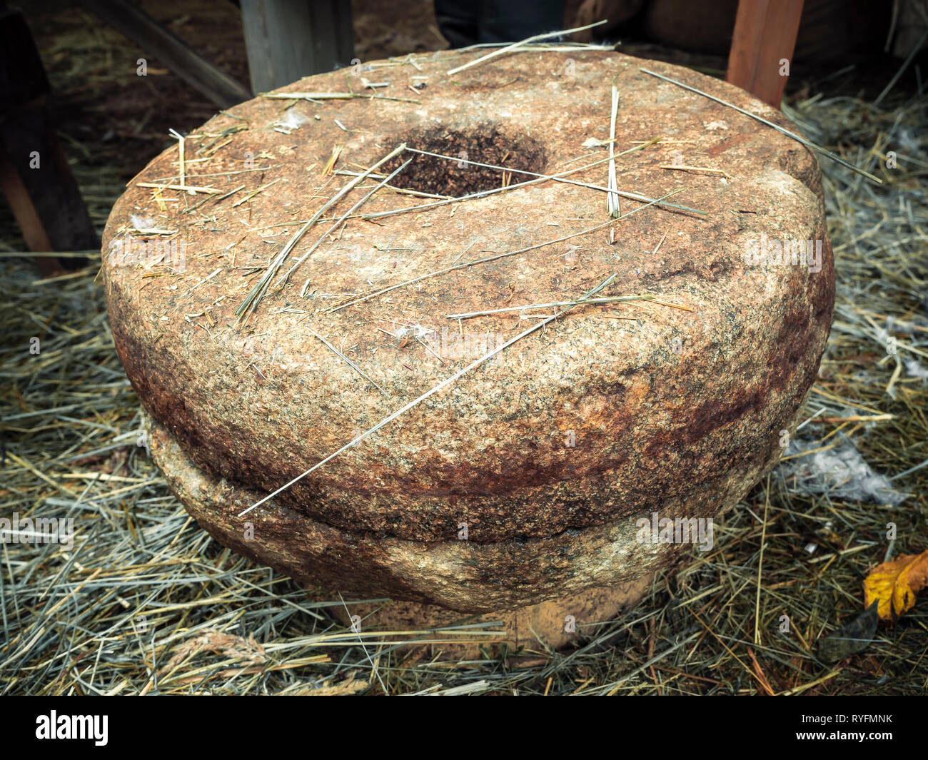 The ancient quern stone hand mill. Old grinding stones straw around ...