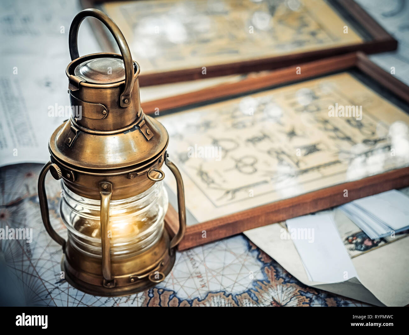 Old brassy ship lantern stands on a map of the seas near pictures with ...