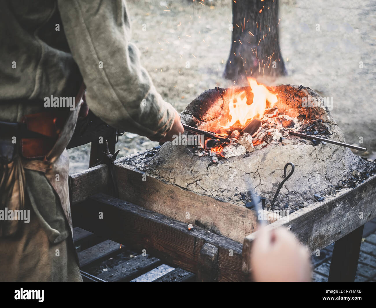 The blacksmith holds the billet over hot coals in a clay oven ...