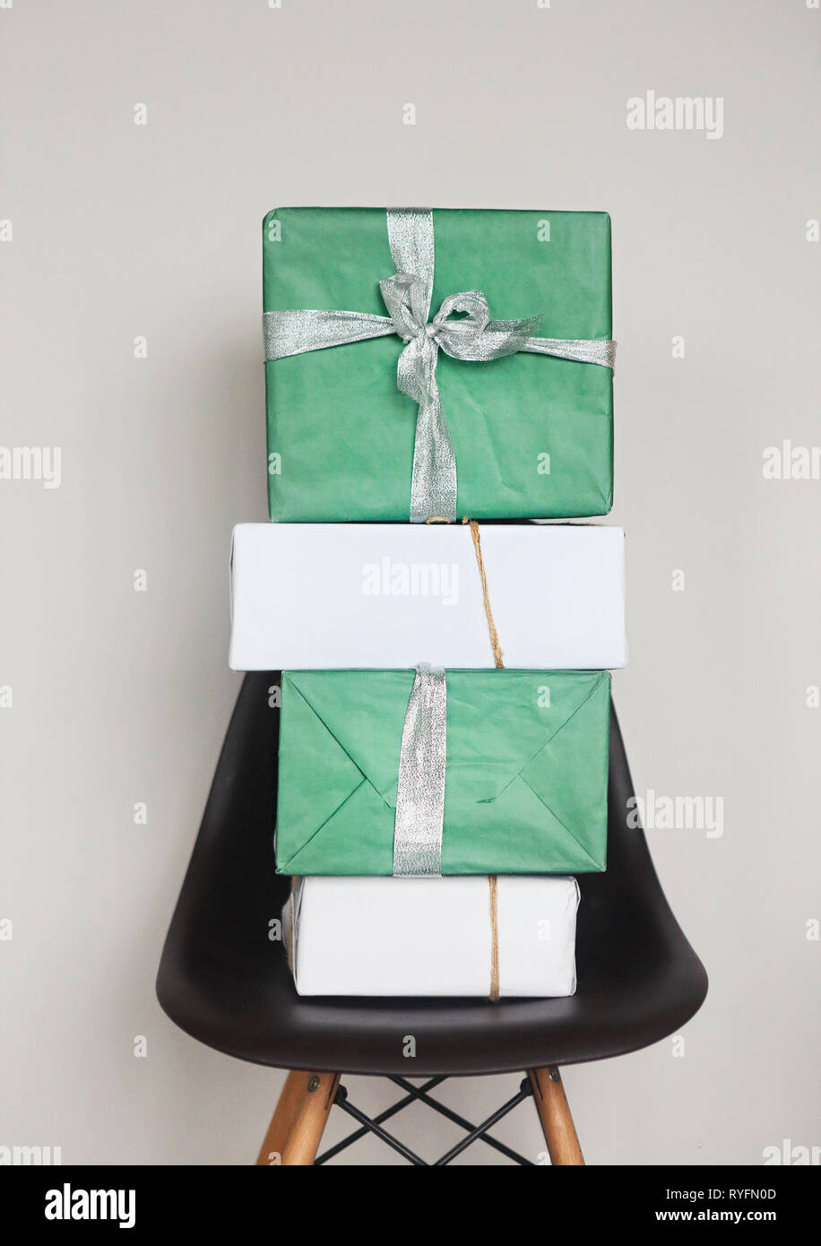 Green and white Christmas gift boxes with red ribbons on chair by the ...