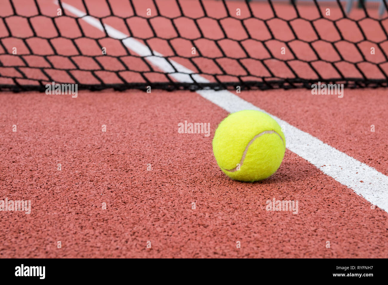 Yellow tennis ball in hard court side white line in net background ...