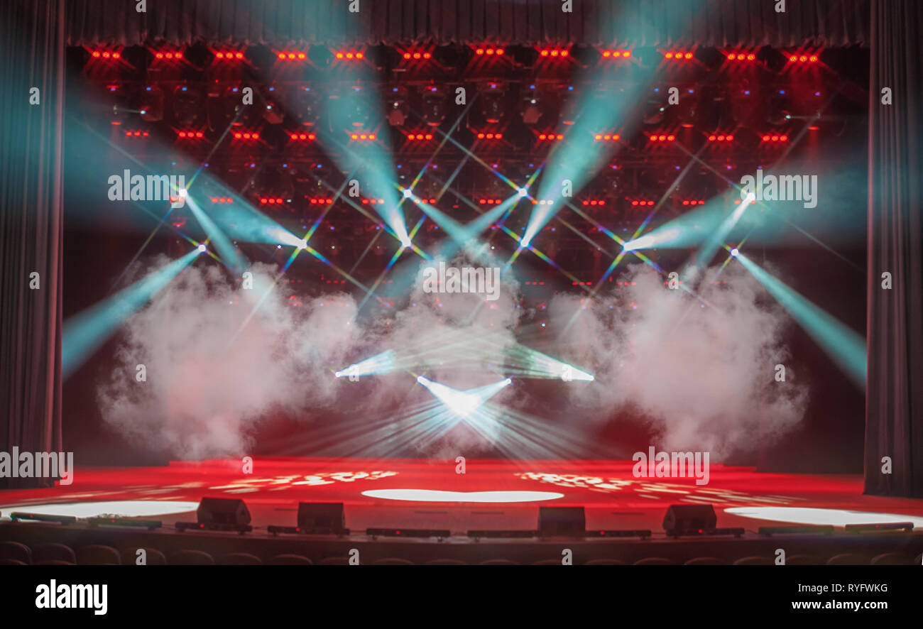 Illuminated empty show stage with fog, red scenic light and white rays ...