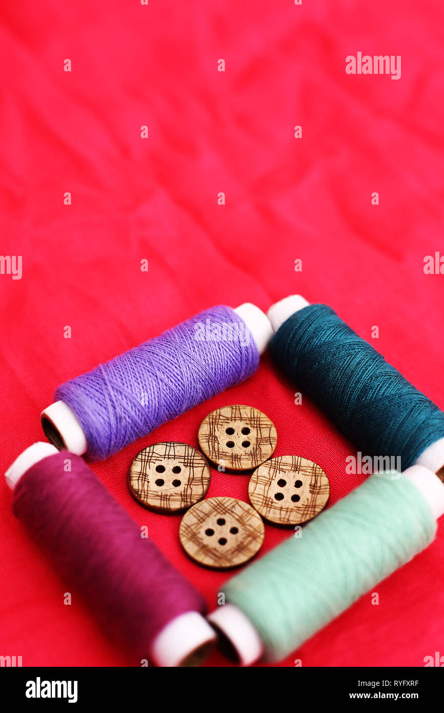 Picture of sewing thread and button. Isolated on the red background ...