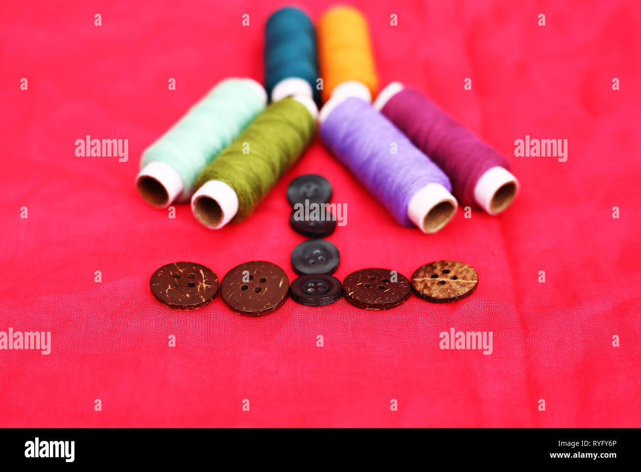 Picture of colored sewing thread and button. Isolated on the red ...