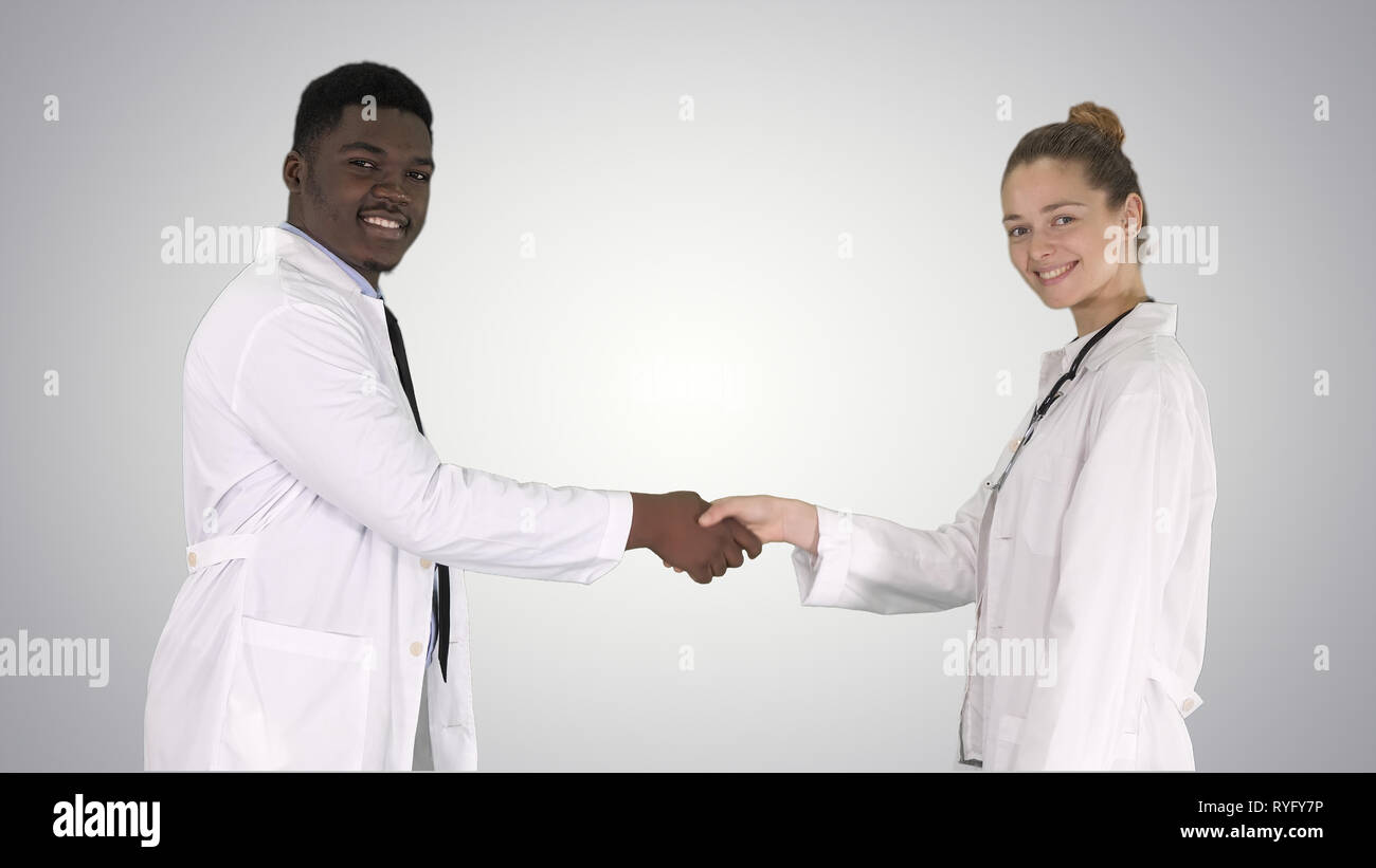 Doctors shaking hands and posing to camera on gradient background Stock ...