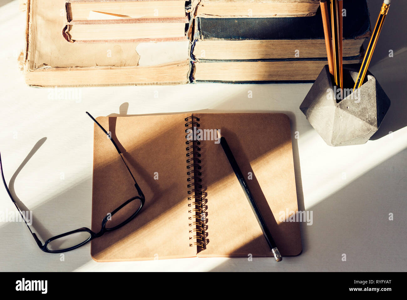 Stack of old books, textbook, glasses and pencils in office background ...