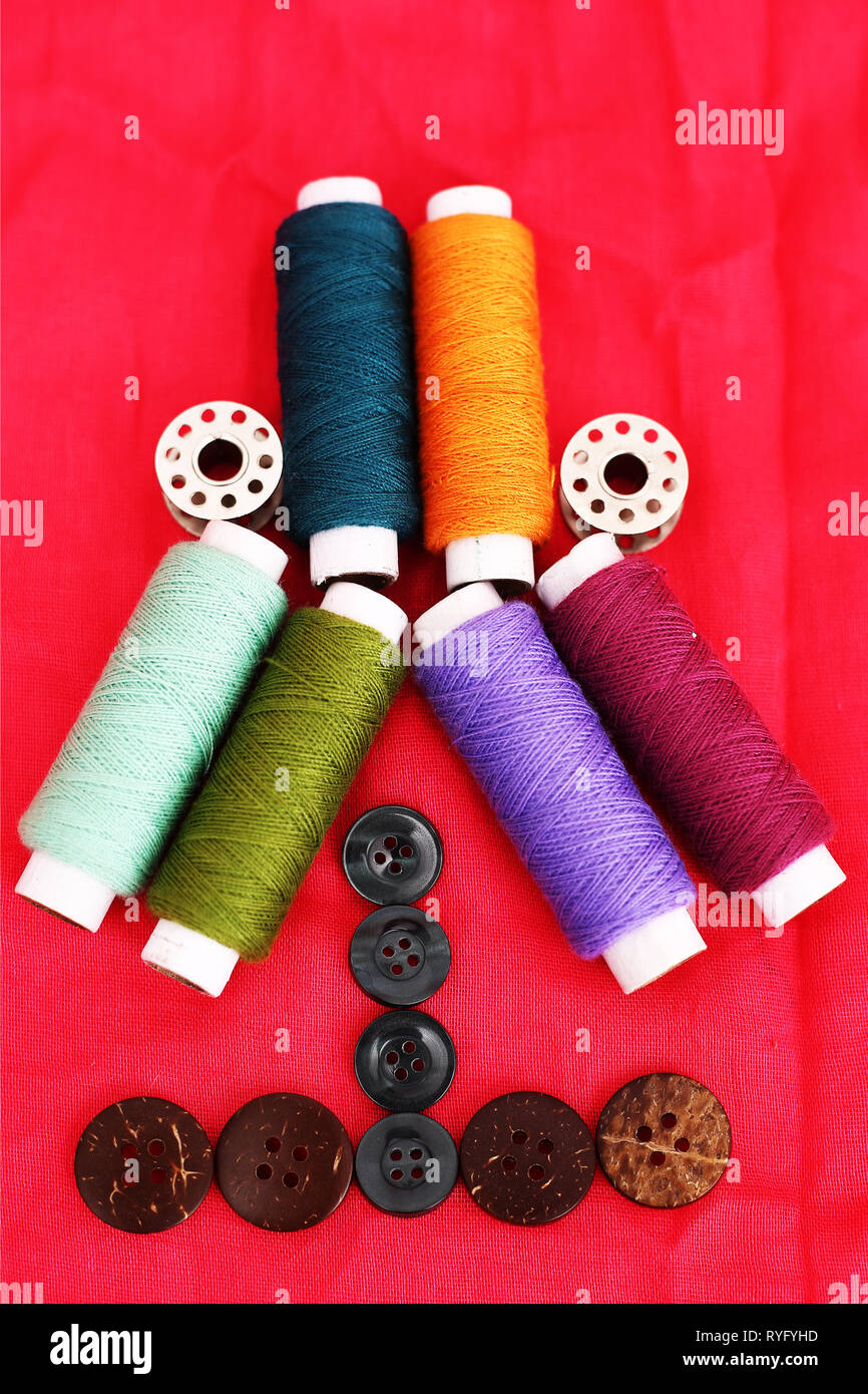 Portrait of sewing thread, bobbin and button. Isolated on the red ...