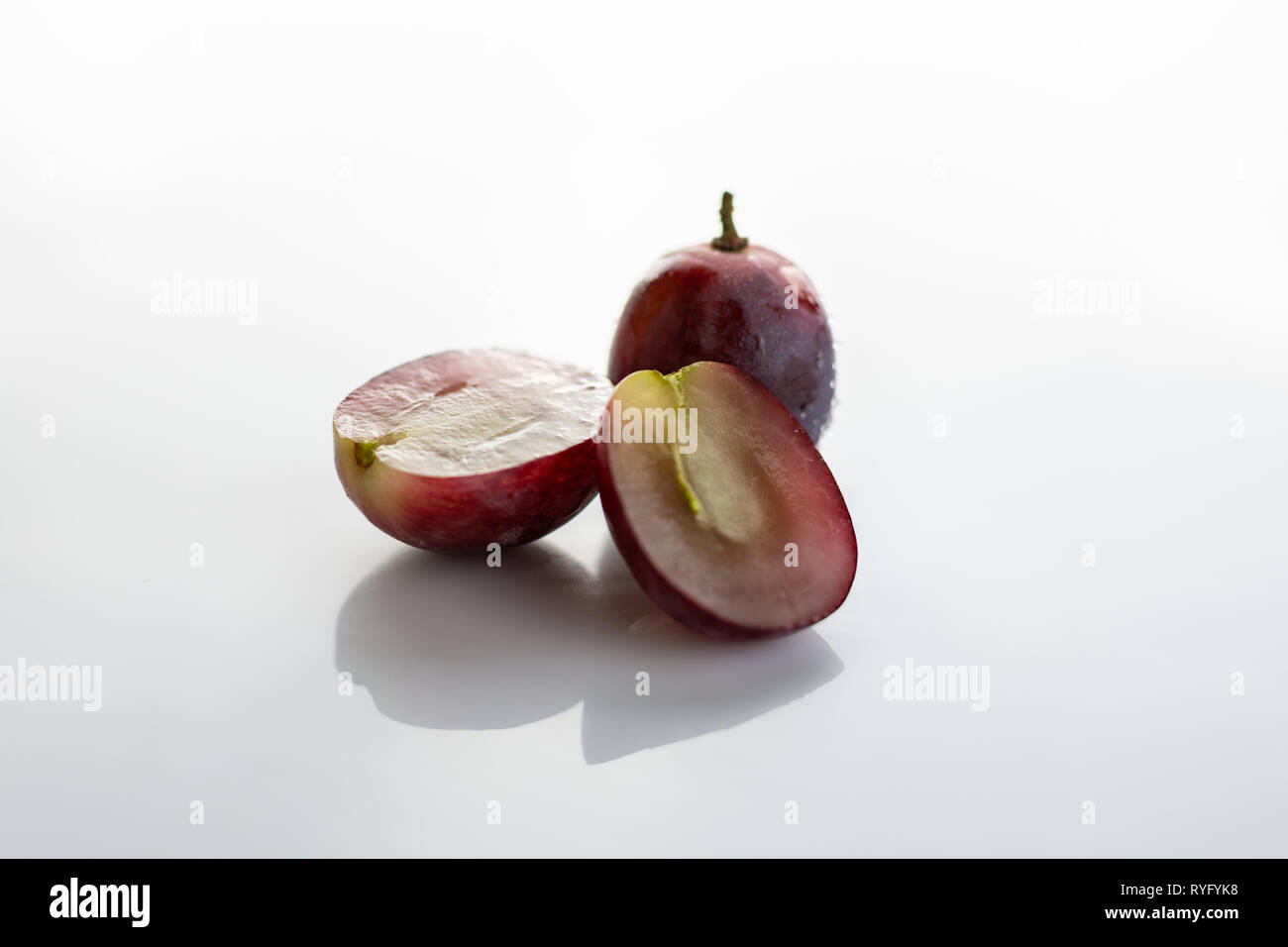 Split red grape isolated on white background Stock Photo - Alamy