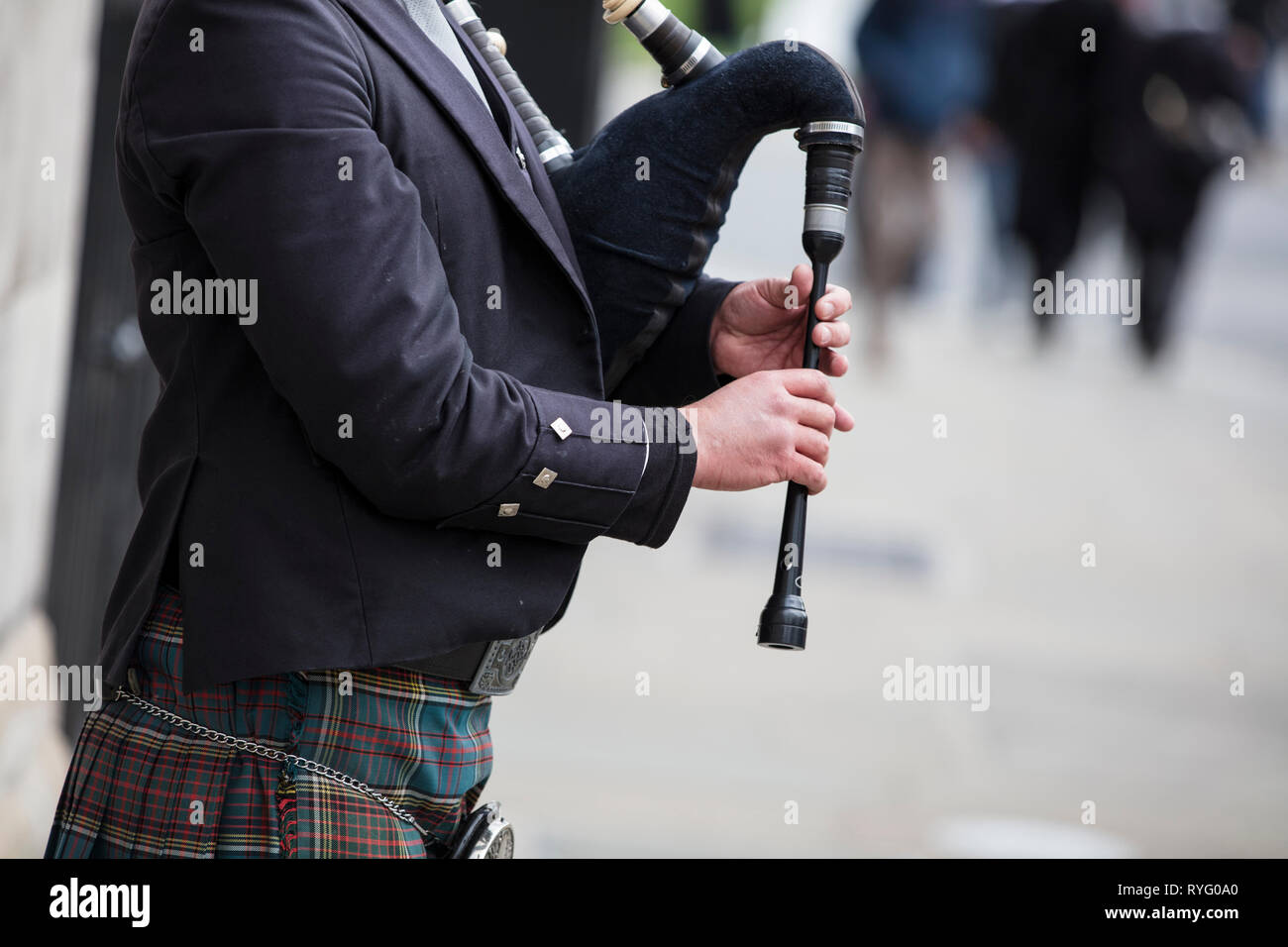 Scottish bagpiper dressed in traditional dress performing on the street ...