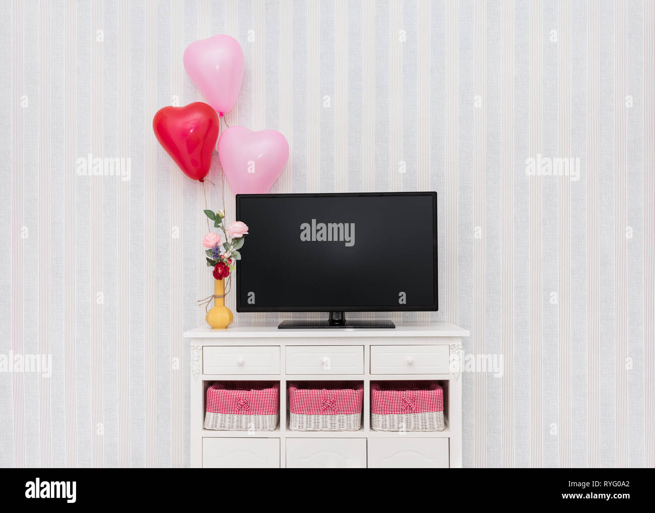 Interior wall with cabinet, tv, flowers and balloons centered in frame ...