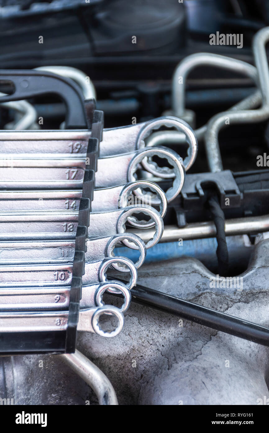 Vertical close up view of car engine bay and specialized set of tools ...