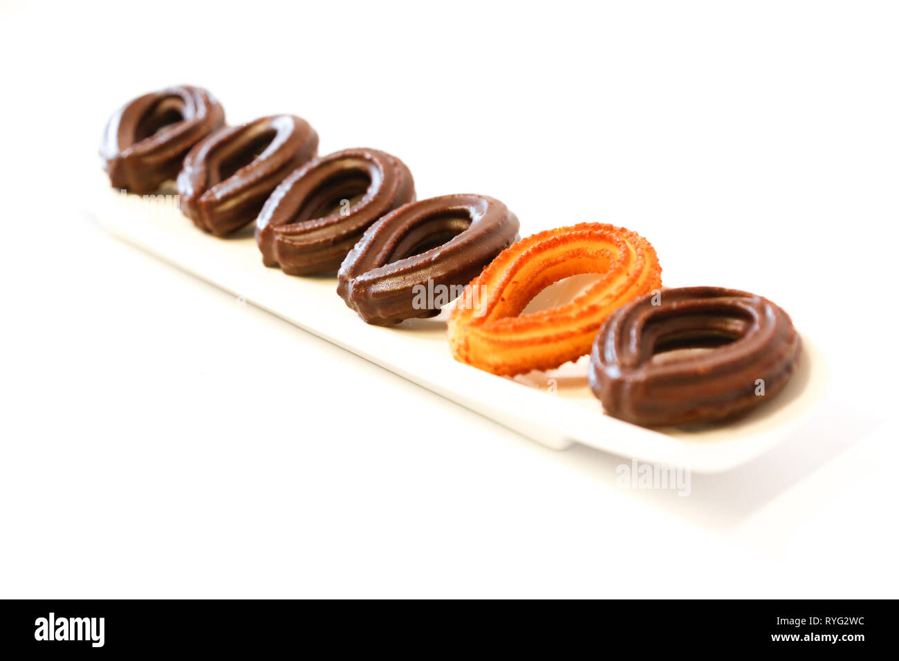 small chocolate spanish fritters in a white dish on white background ...