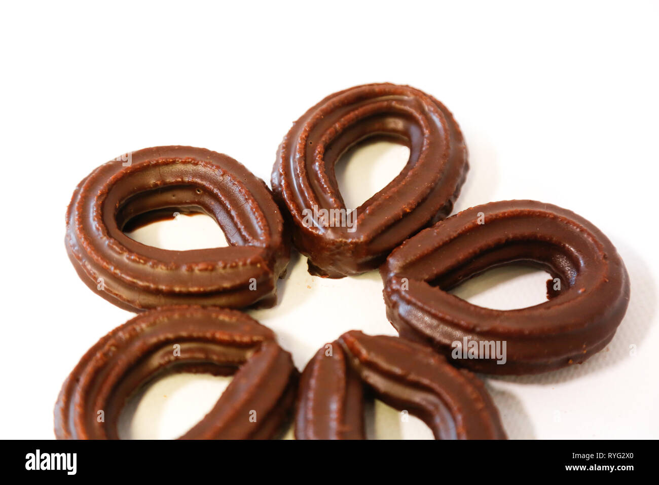 small chocolate spanish fritters on flower shape on white background ...