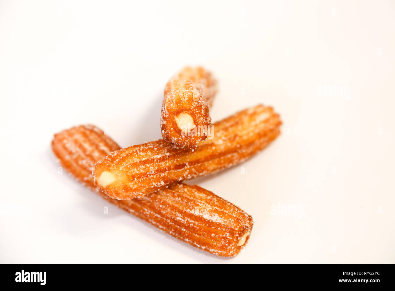 spanish fritters filled with cream on white background on white dish ...