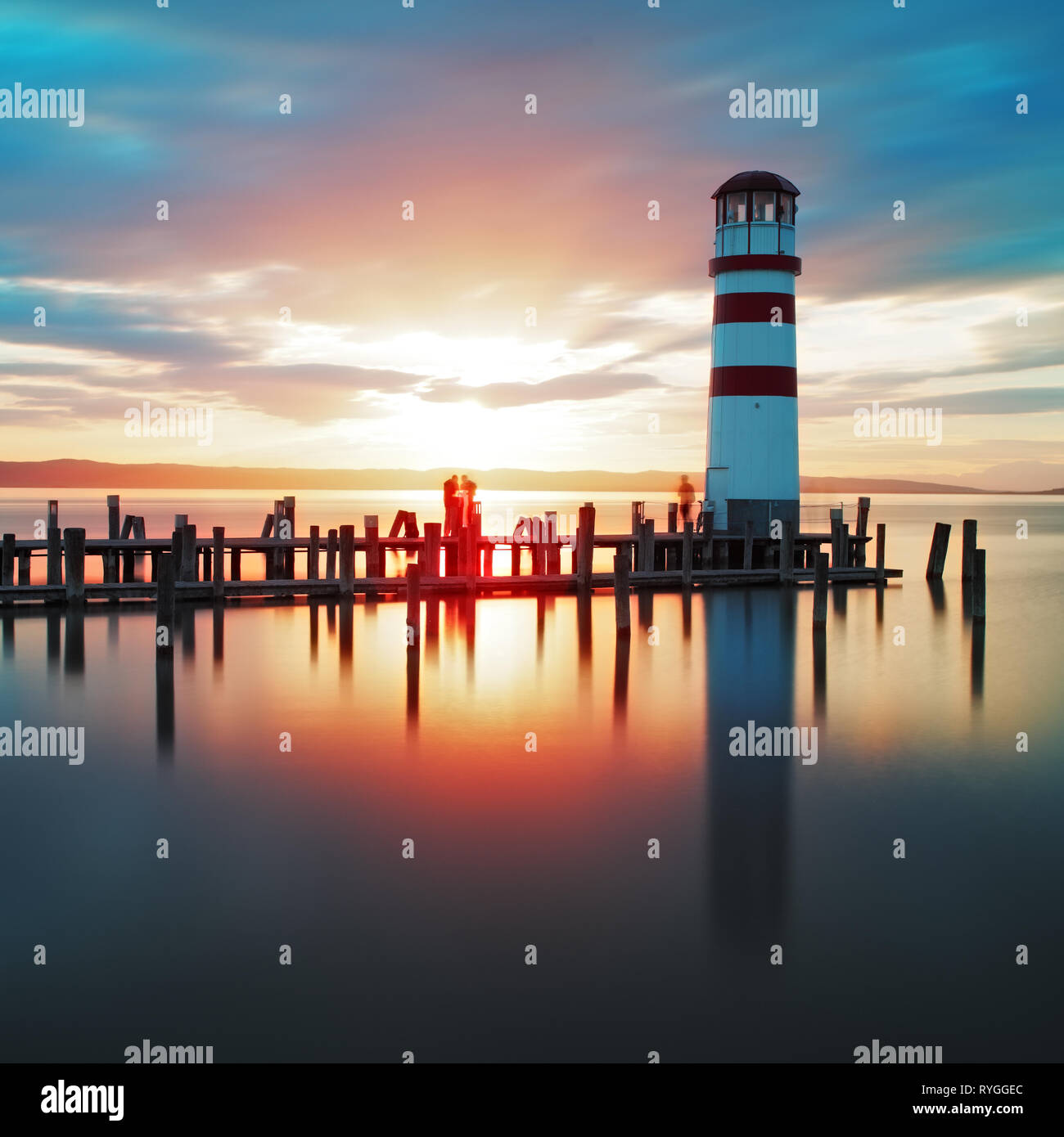Ocean sunset with lighthouse Stock Photo - Alamy