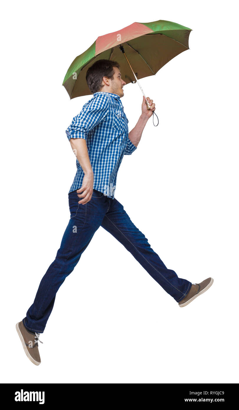 Side view of a man balancing with an umbrella. guy jumps over a puddle ...