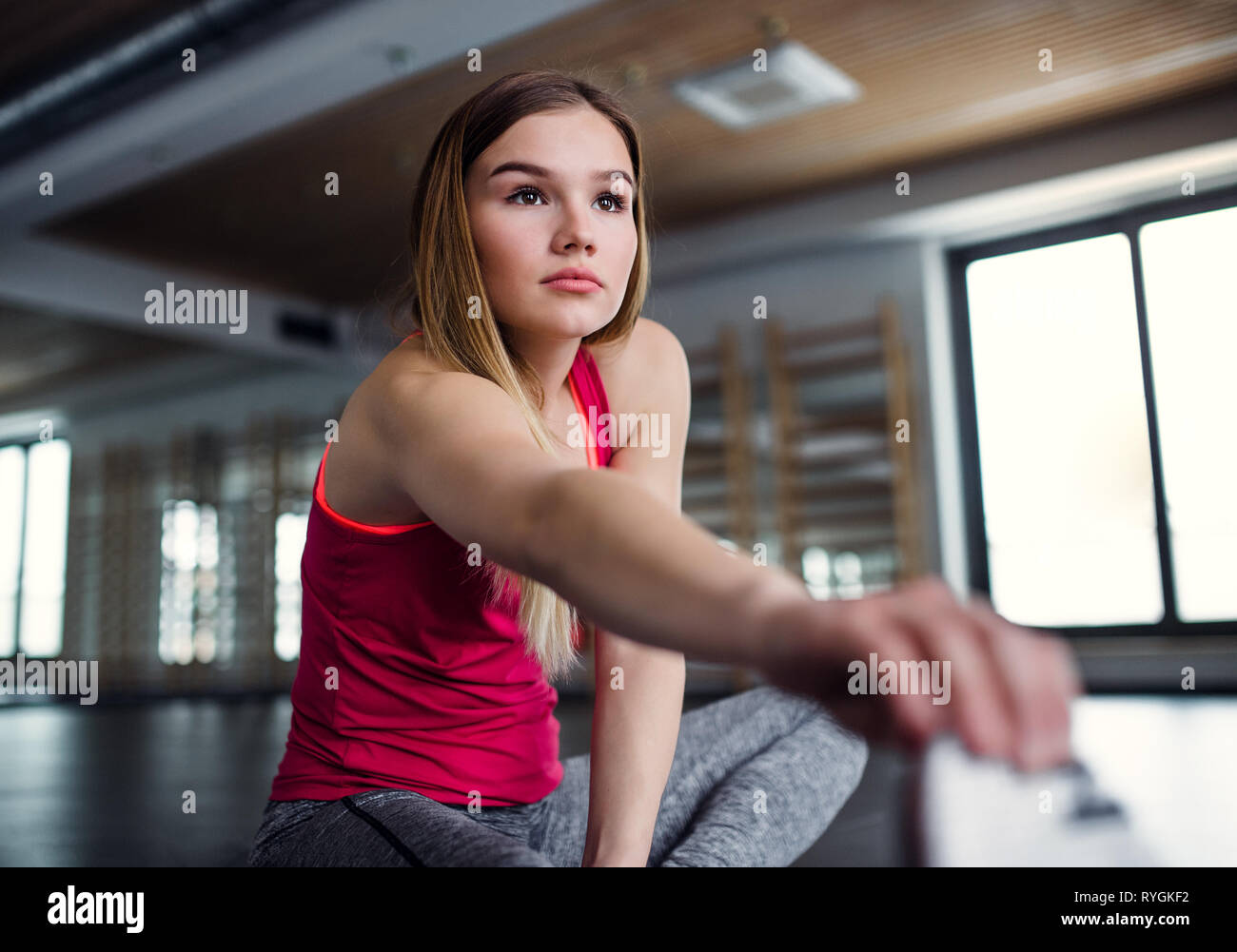 A portrait of a beautiful young girl or woman doing exercise in a gym ...