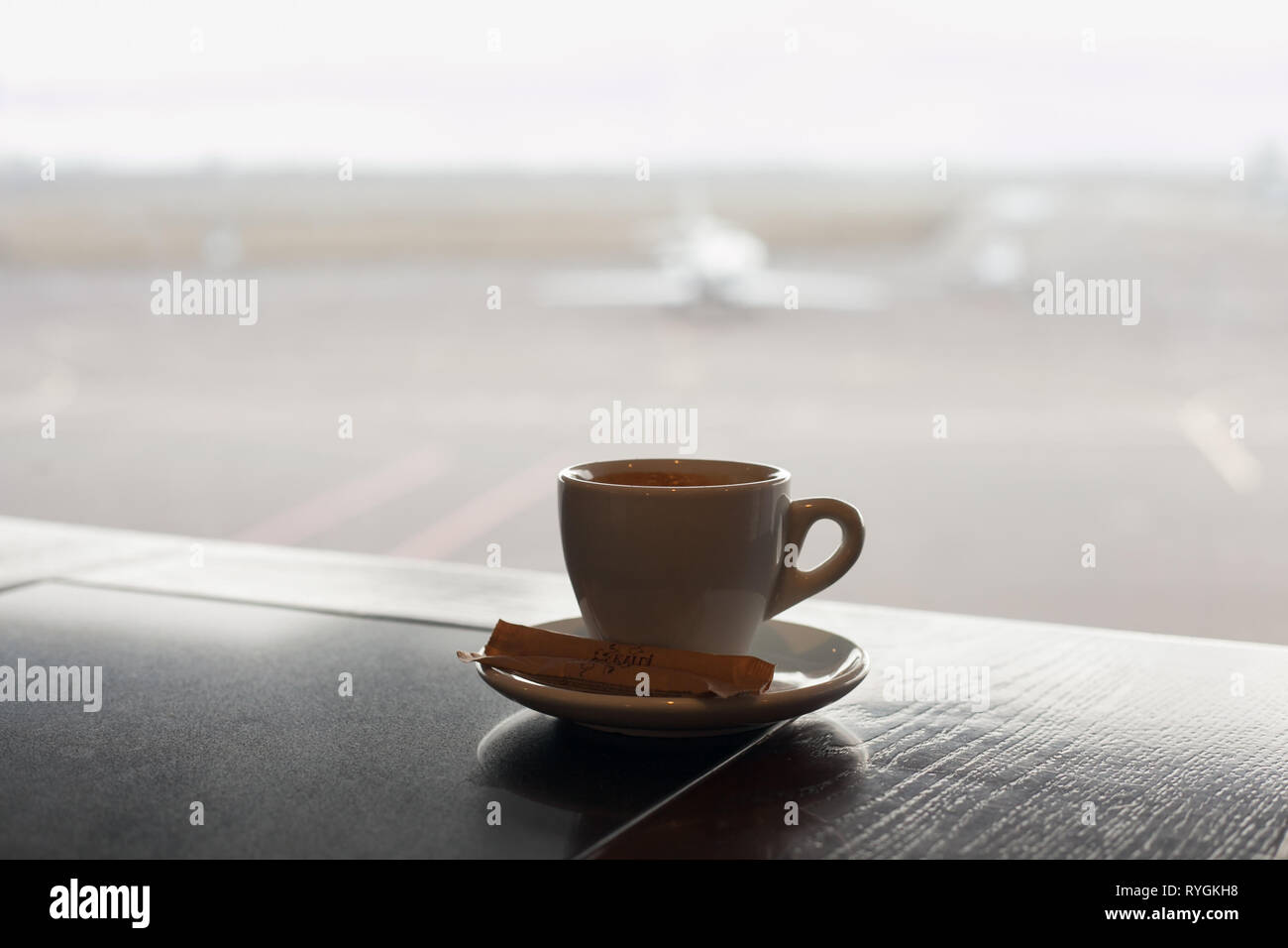 The cup of coffee on the table in airport cafe. View on blurred ...