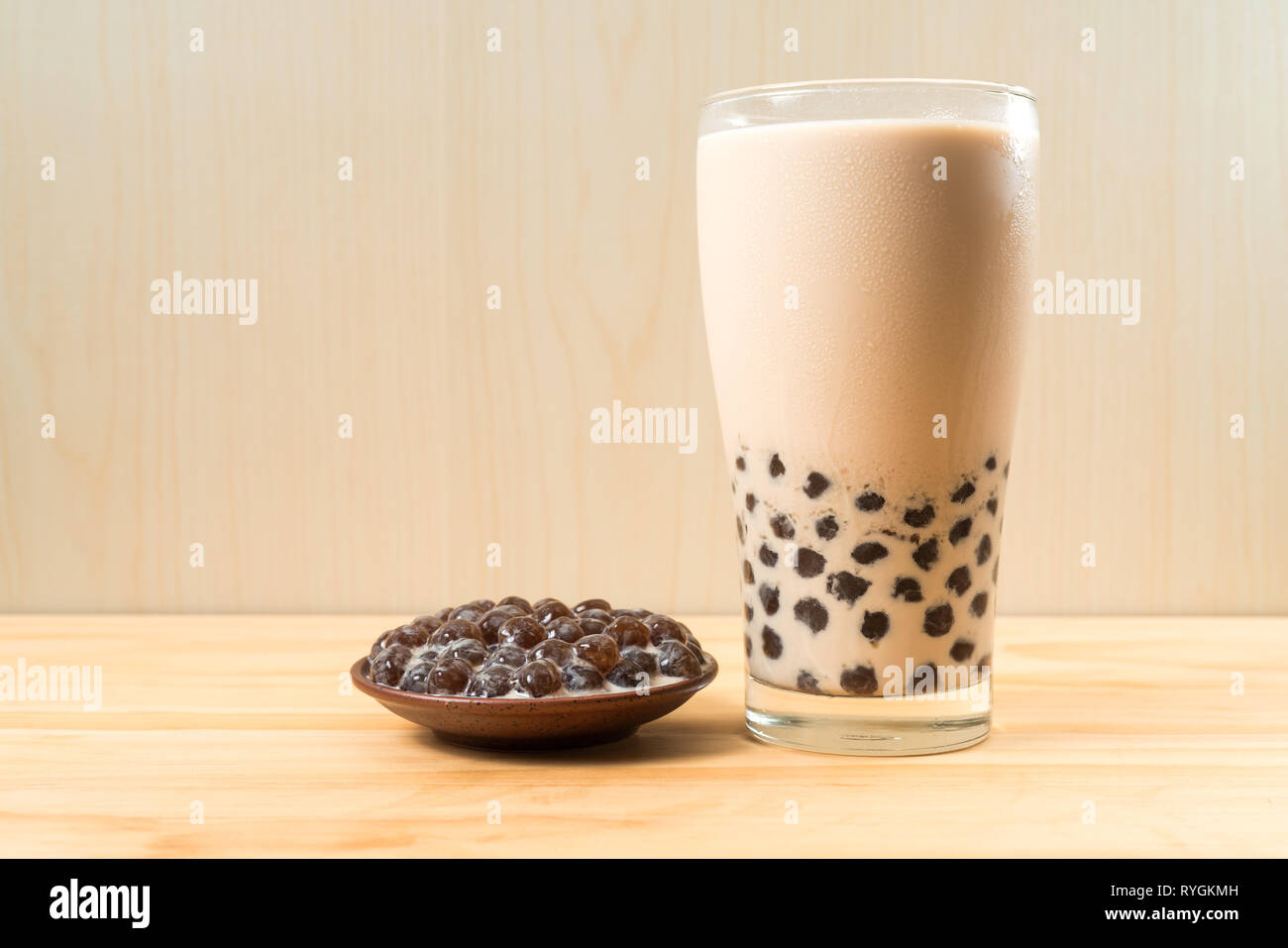 A glass cup of pearl milk tea (also called bubble tea) and a plate of ...