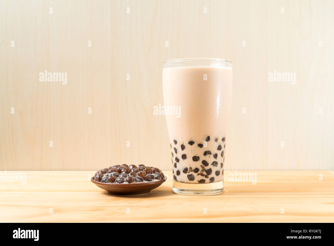 A glass cup of pearl milk tea (also called bubble tea) and a plate of ...