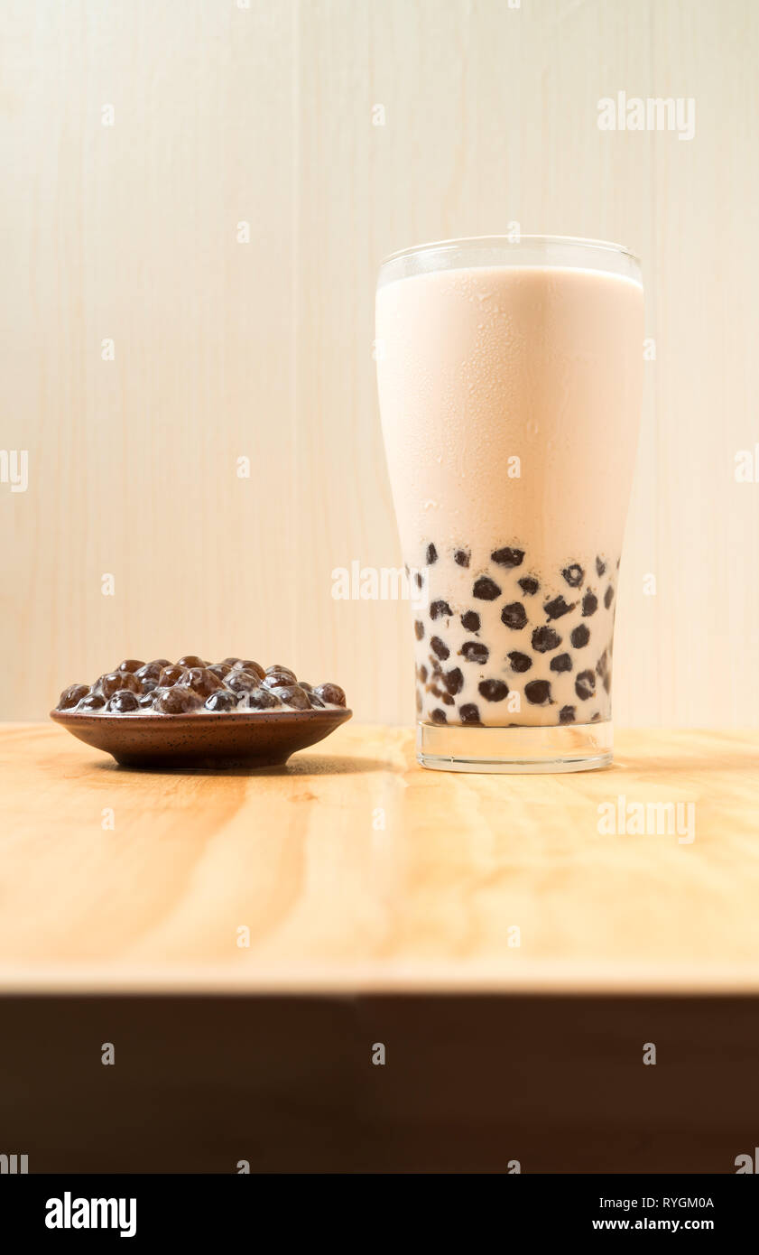 A glass cup of pearl milk tea (also called bubble tea) and a plate of ...